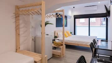 Quarto moderno com estrutura de cama de madeira, uma pequena mesa de cabeceira, um banco e um cabideiro.