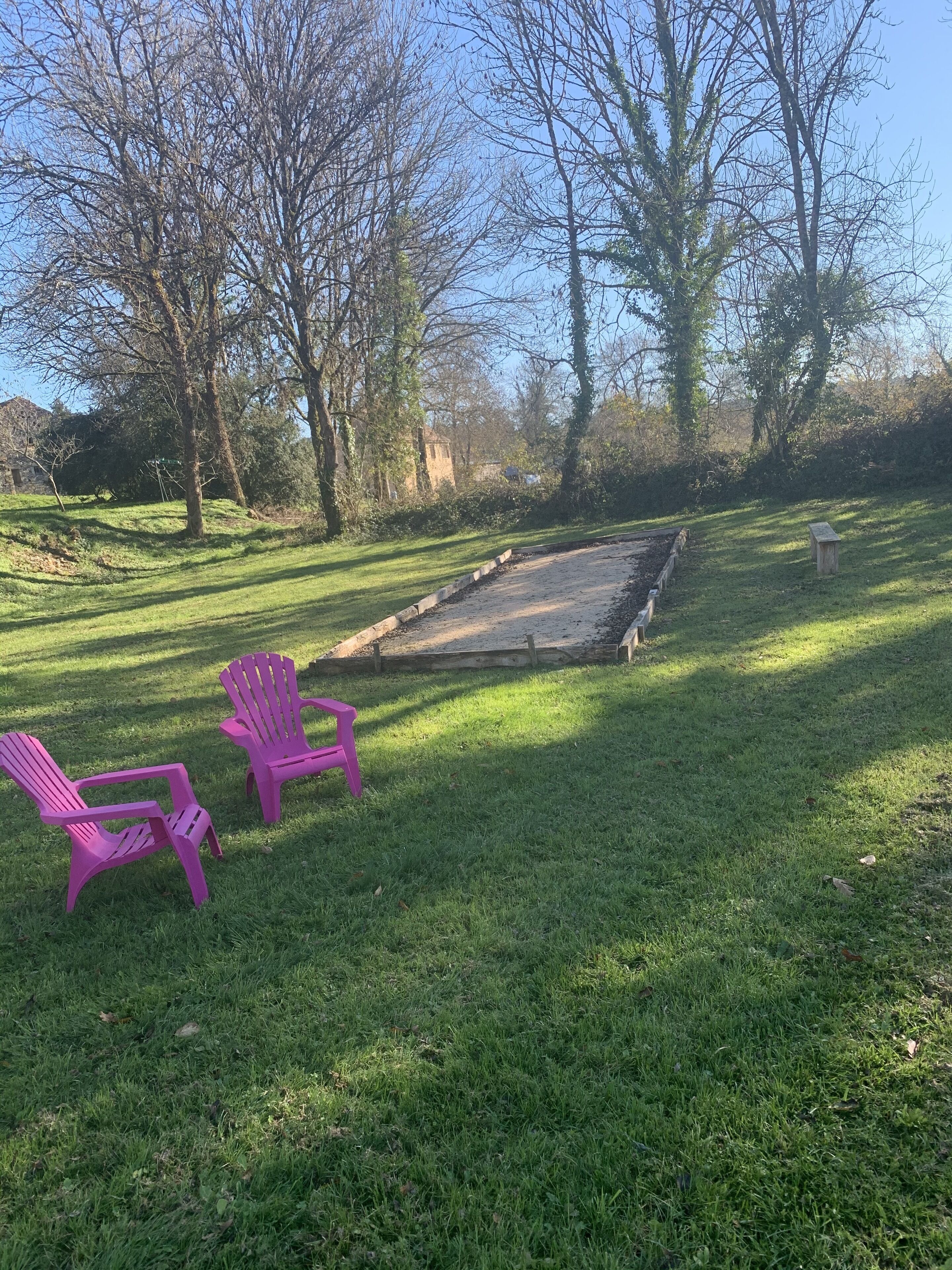 Uma área externa com grama, duas cadeiras Adirondack cor-de-rosa e um deck de madeira.