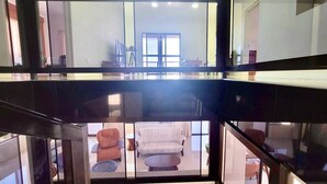 Um interior moderno com uma grande janela de vidro, um sofá, uma cadeira e uma pequena mesa redonda.