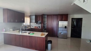 Cozinha moderna com armários de madeira escura, geladeira de aço inoxidável e piso ladrilhado.