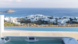 Uma banheira de hidromassagem com vista para uma cidade costeira e o mar.