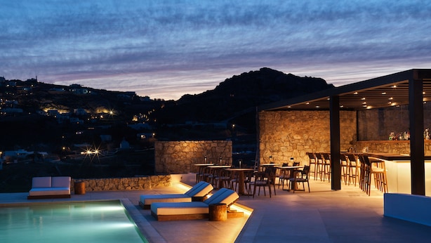 Área de piscina no terraço com espreguiçadeiras e um bar.