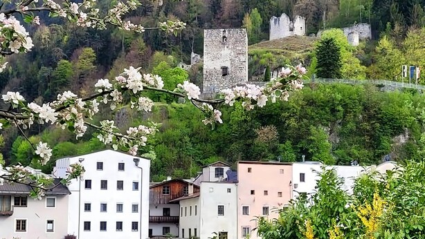 Uma cidade com um castelo numa colina, edifícios modernos e um rio.