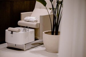 Um espaço de spa com uma cadeira de massagem, uma pia branca e uma planta em vaso.