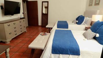 Quarto de hotel com duas camas, uma televisão, um aparador e um banco.