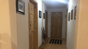 Um corredor estreito com portas de madeira e tapetes listrados em preto e branco no chão.