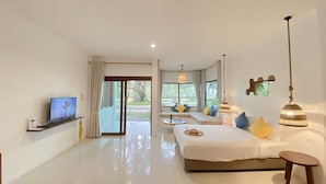 Quarto de hotel moderno com uma cama grande, TV, área de estar com almofadas e vista para o exterior.