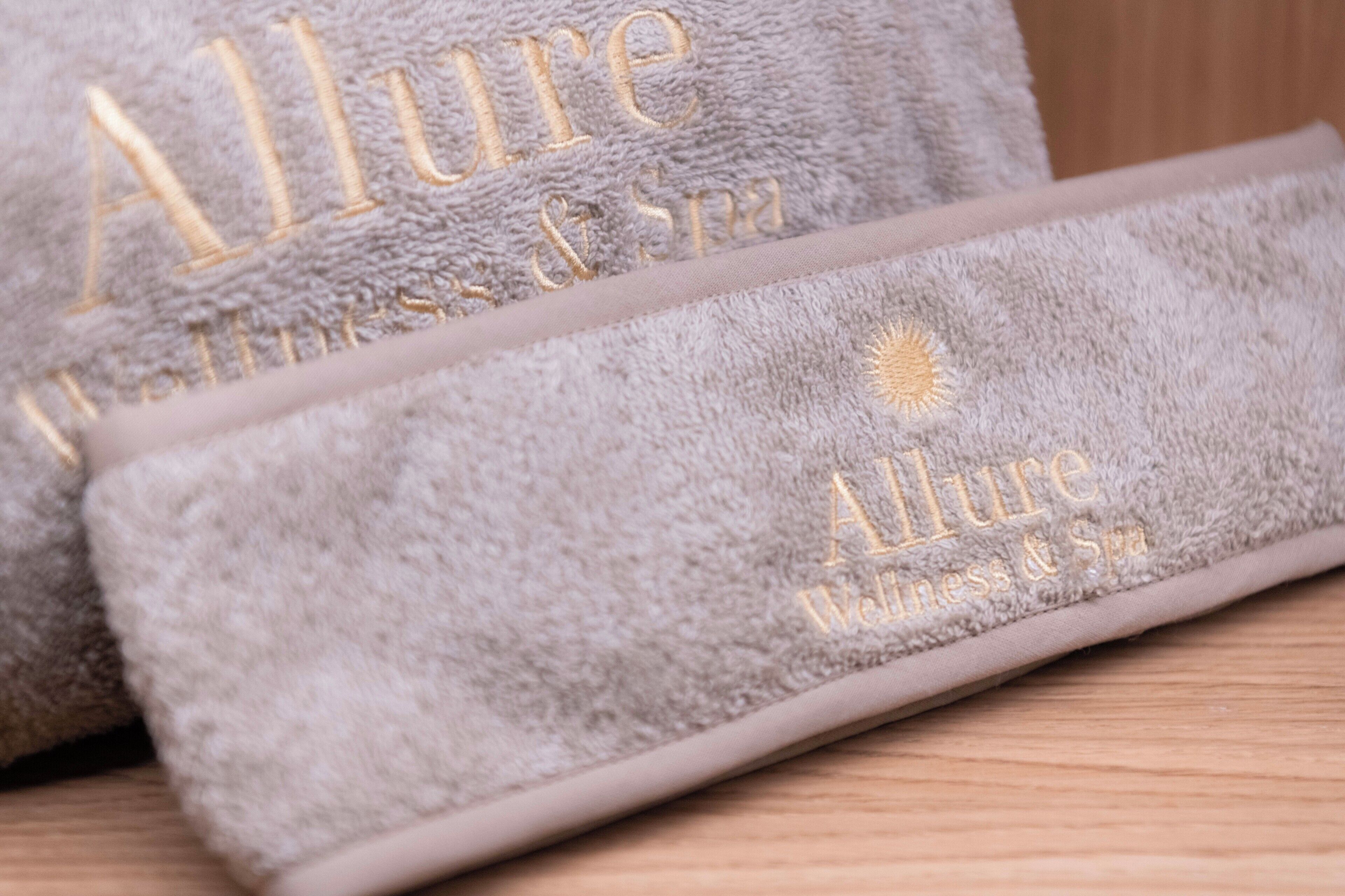Duas toalhas com bordado que diz "Allure Wellness & Spa".