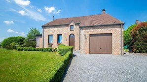 Uma casa de dois andares com fachada de tijolos, telhado telhado e entrada por um caminho de pedras.