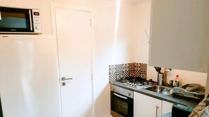 Cozinha compacta com micro-ondas, fogão, forno e pia.
