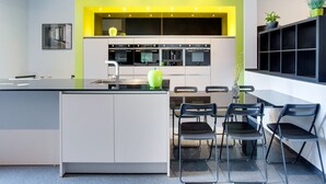 Cozinha moderna com ilha central, eletrodomésticos embutidos e área de estar com cadeiras.