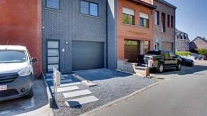 Uma rua residencial com casas modernas, um caminho de cascalho e carros estacionados.