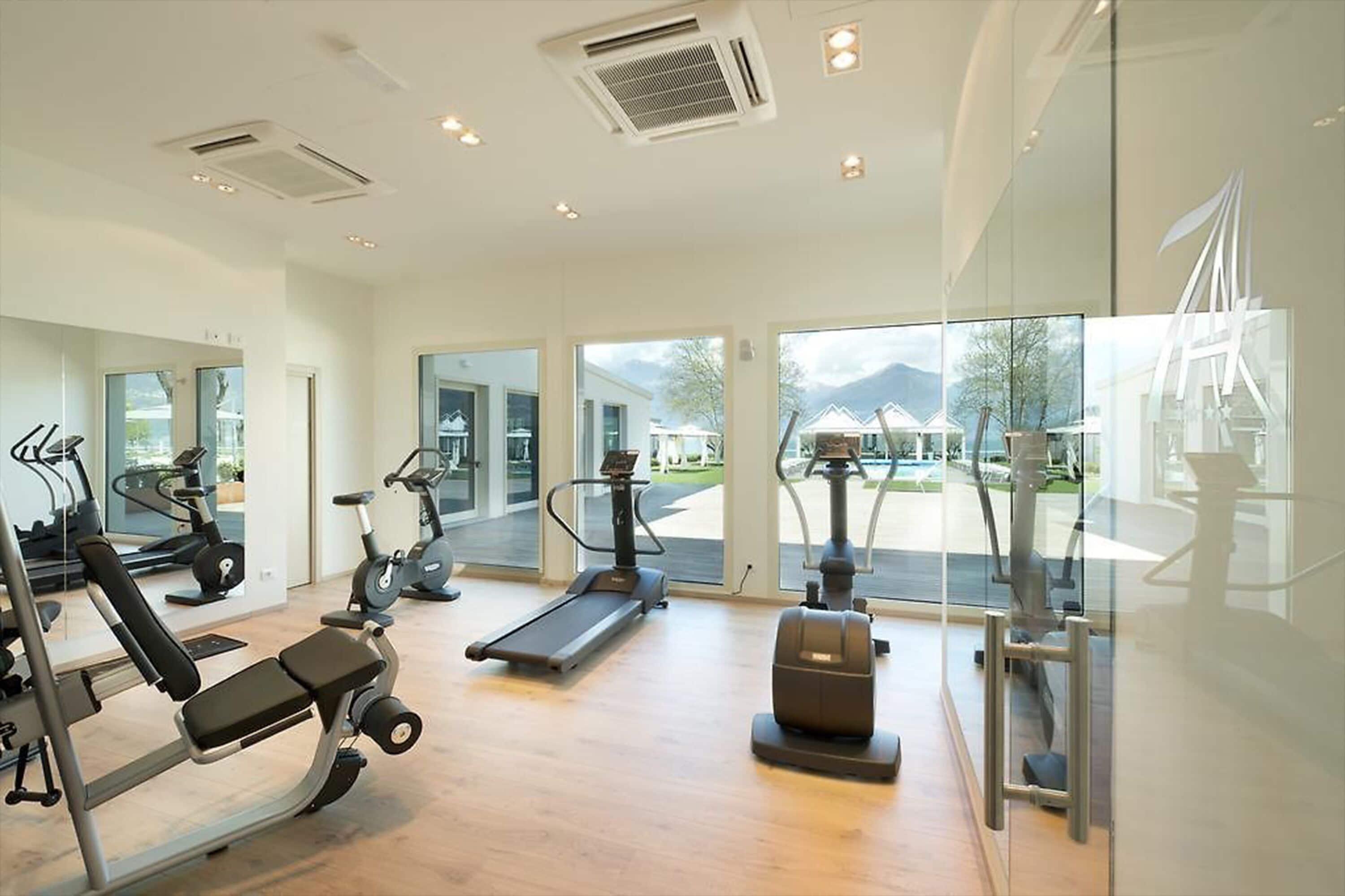 Uma academia com equipamentos de cardio, aparelhos de musculação e esteira.