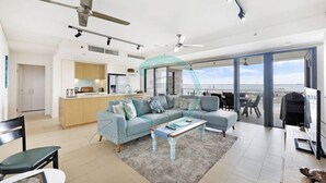 Sala de estar moderna com sofá, mesa de centro e vista para a cidade através de grandes janelas.