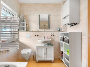 Uma casa de banho moderna com sanita, lavatório e armário de armazenamento.