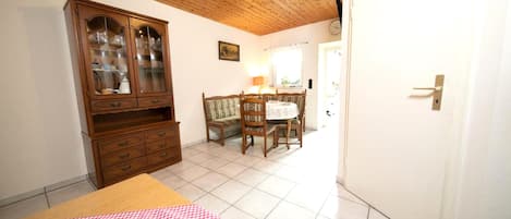 Um quarto com um armário de madeira, uma mesa de jantar com cadeiras e uma cama com colcha xadrez.