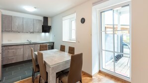 Uma cozinha moderna com armários cinzentos, uma ilha central e um espaço de refeições com mesa e cadeiras.