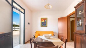 Uma sala de jantar com uma mesa, cadeiras, uma tigela, um quadro e um armário.