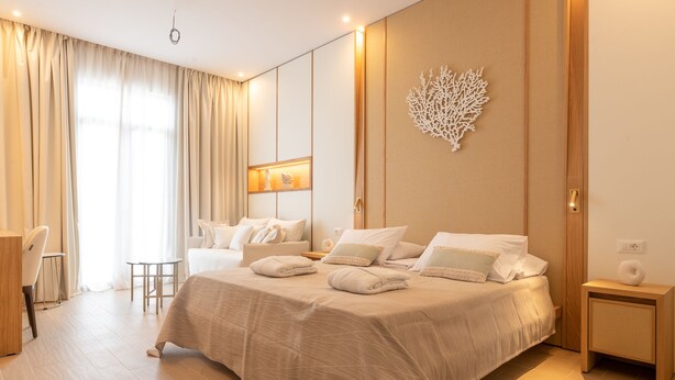 Quarto de hotel moderno com uma cama grande, uma escrivaninha e uma cadeira.