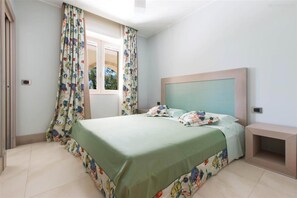 Um quarto com cama, cortinas, janela e mesa de cabeceira.