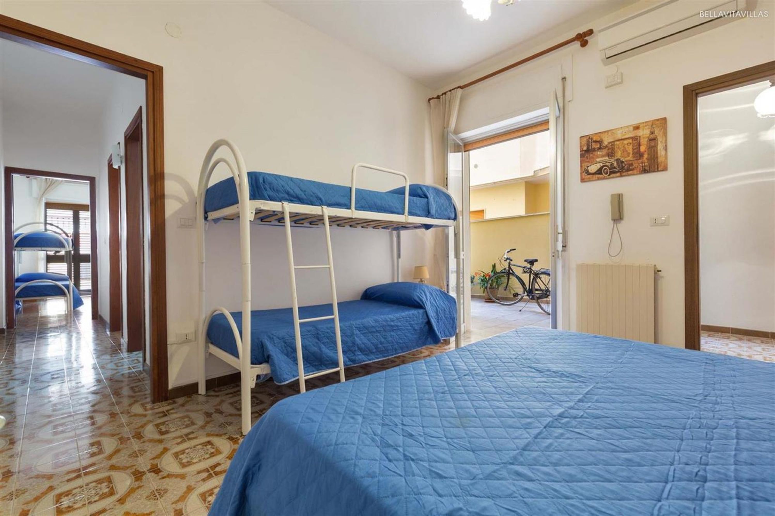 Quarto com beliches, uma cama grande, uma bicicleta e um radiador.