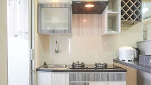 Uma cozinha compacta com fogão a gás, pia e micro-ondas.