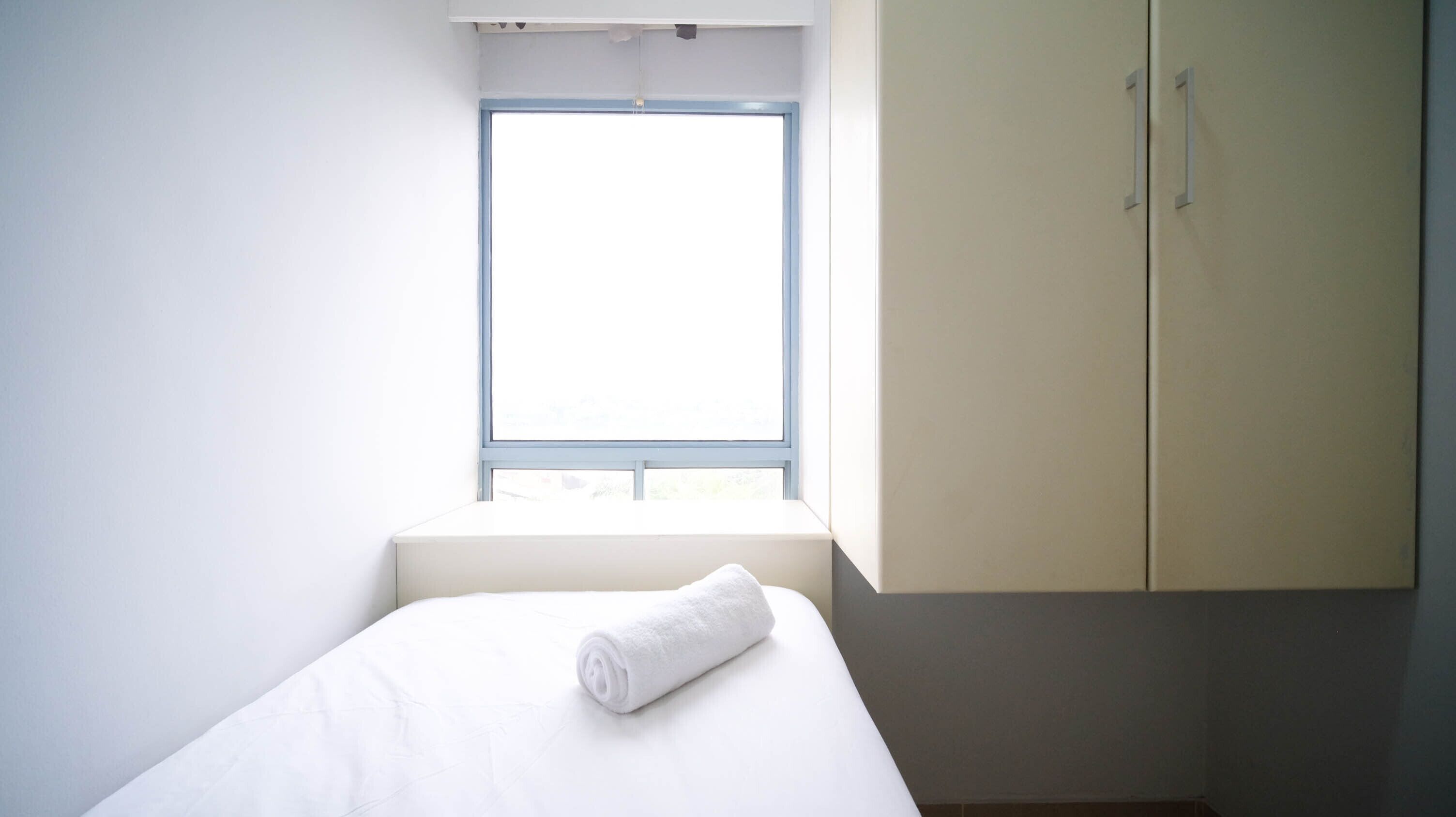 Quarto com uma cama de solteiro, janela e guarda-roupa.