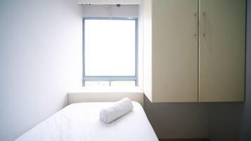 Quarto com uma cama de solteiro, janela e guarda-roupa.