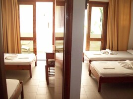 Quarto de hotel com duas camas de solteiro, uma escrivaninha de madeira e uma cadeira.