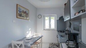 Uma cozinha compacta com mesa, cadeiras, cafeteira e janela com vista.