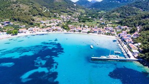 Uma cidade costeira com um porto de iates, casas à beira-mar e montanhas ao fundo.