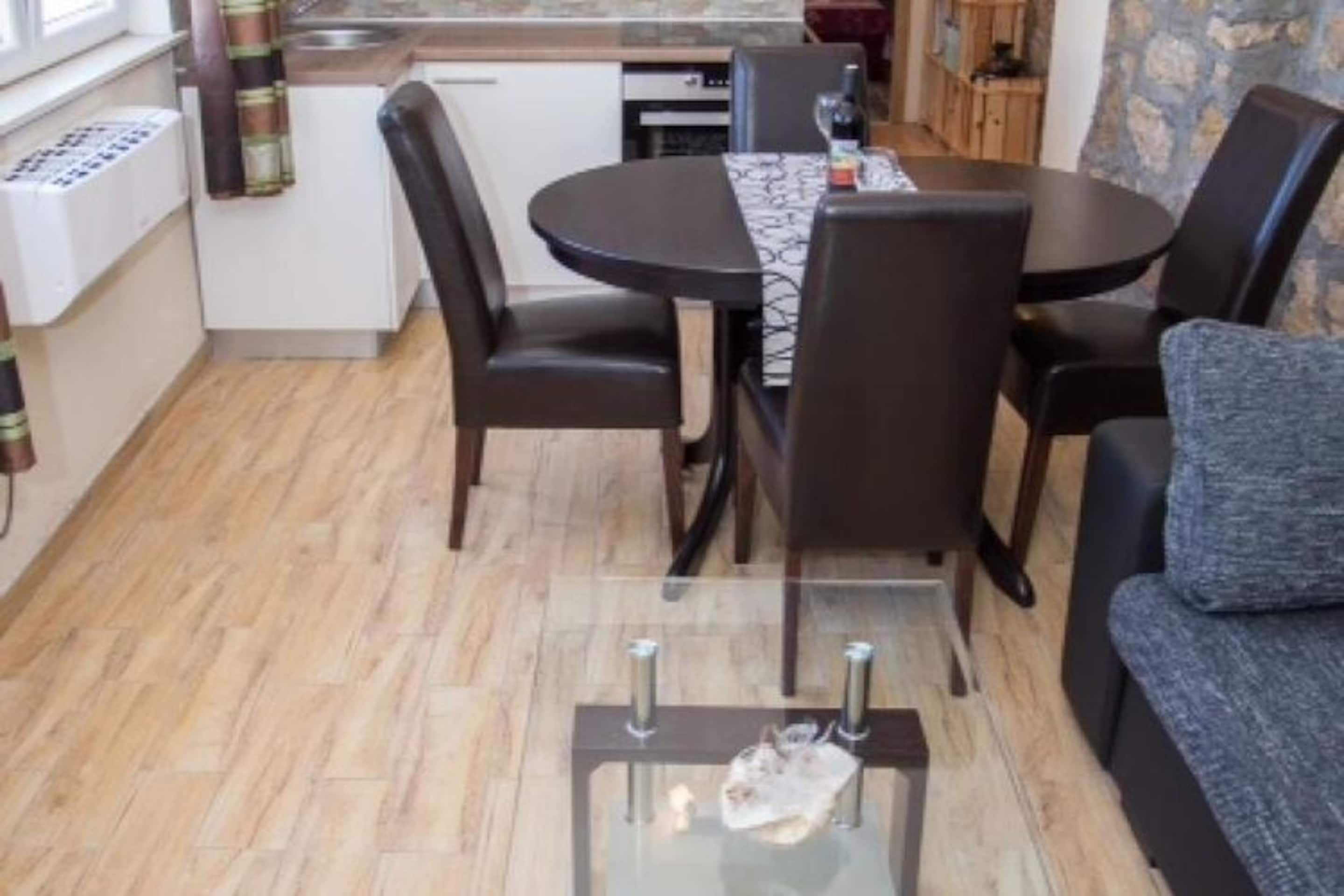 Um espaço compacto com cozinha compacta, área de refeições com mesa redonda e cadeiras, e um sofá.