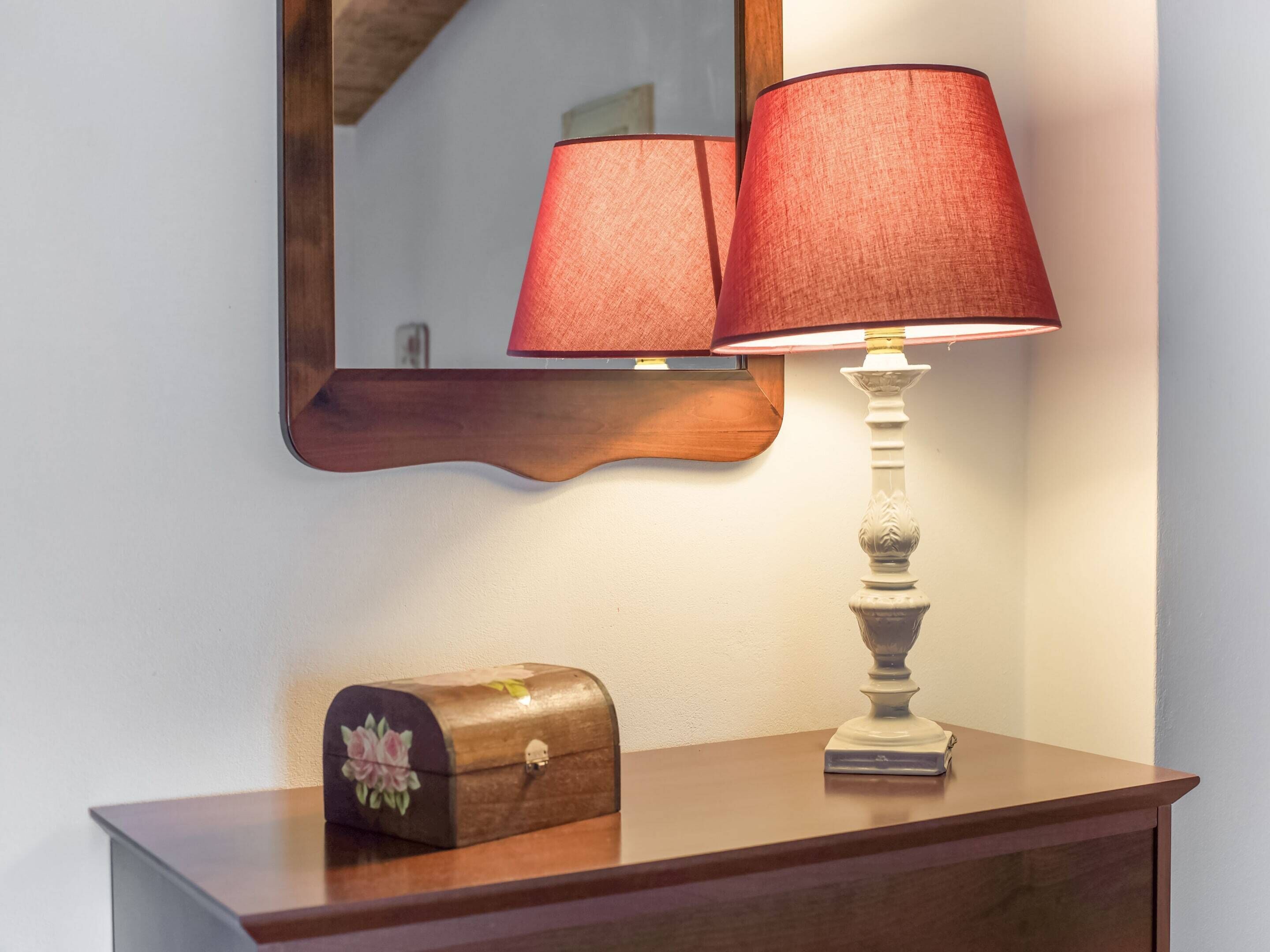 Uma mesa de cabeceira de madeira com uma luminária e uma caixa decorativa de madeira.
