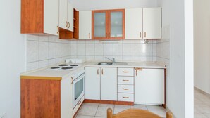 Uma cozinha com armários brancos, armários superiores de madeira, um fogão, forno e pia.