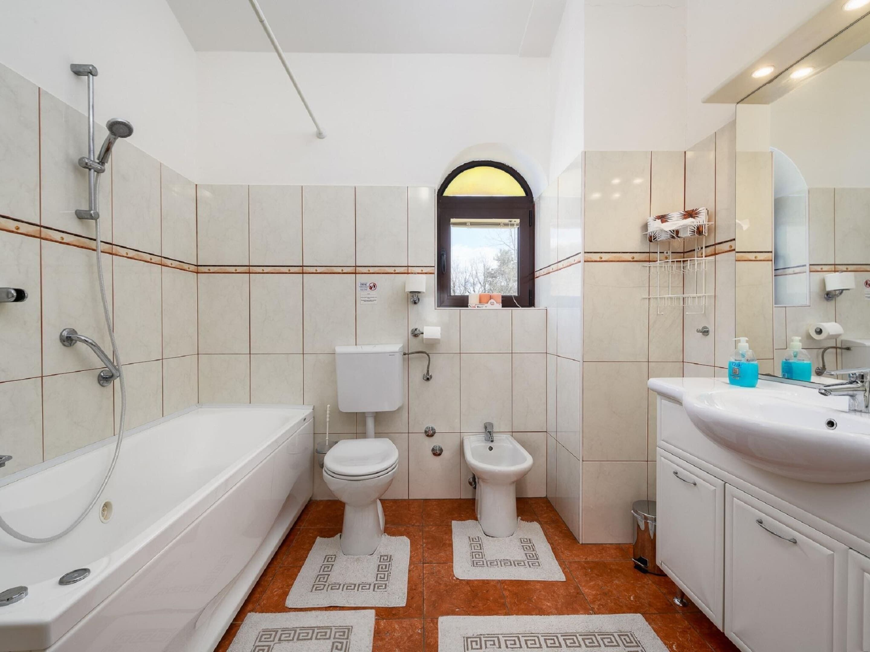 Uma casa de banho moderna com banheira, sanita, bidé e lavatório.