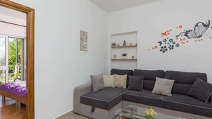 Uma sala de estar moderna com um sofá seccional cinza, uma mesa de centro de vidro e vista através de uma grande janela.