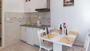 Uma cozinha compacta com armários brancos, um pequeno frigorífico e painel de azulejos.