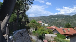 Área residencial com casas, um muro de pedra e vista para colinas ao fundo.
