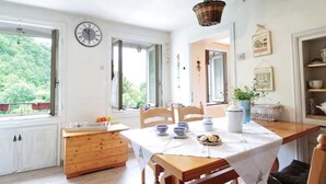 Uma cozinha clara com uma mesa de madeira, cadeiras e um relógio na parede.