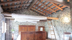 Um quarto rústico com cama de madeira, paredes de pedra e teto de madeira.