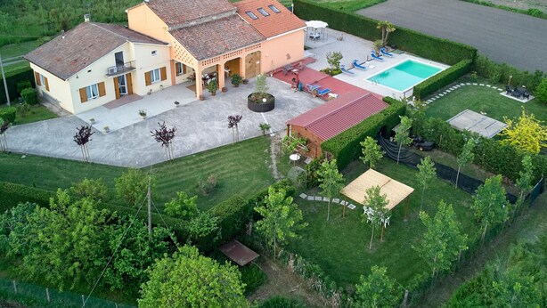 Uma casa de dois andares com piscina, rodeada por um gramado e jardim bem cuidados.