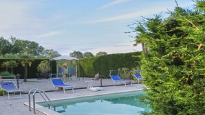 Piscina com espreguiçadeiras e área de estar coberta.