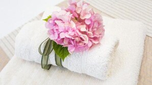 Toalha branca com um buquê de flores cor-de-rosa sobre uma superfície listrada.
