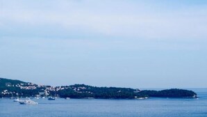 Vista costeira com uma pequena ilha, barcos e edifícios na orla.