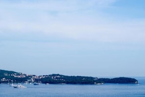 Vista costeira com uma pequena ilha, barcos e edifícios na orla.