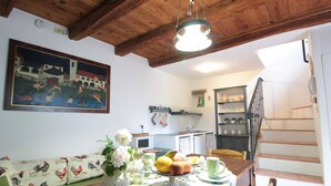 Uma sala de jantar com mesa de madeira, cadeiras, um vaso com flores e um quadro na parede.