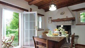 Uma sala de jantar com mesa de madeira, cadeiras e lareira.