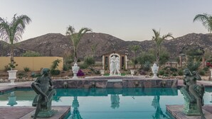Área de piscina com estátuas, uma fonte e um edifício com cúpula ao fundo.