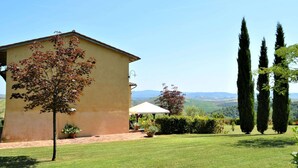 Uma casa com jardim, pérgola e vista para colinas distantes.