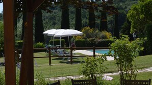 Uma área de pátio com mesa e cadeiras, piscina e cerca de madeira.